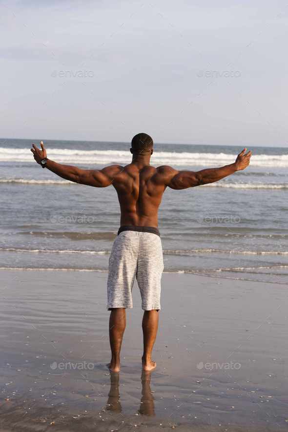 Mid adult man standing on beach, arms outstretched, rear view Stock ...