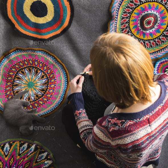 Overhead view of woman sitting on floor crocheting, surrounded by ...