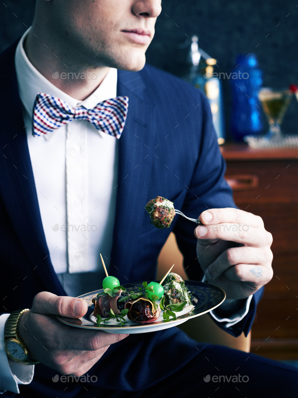 Retro styled man eating plate of appetizers Stock Photo by Image-Source