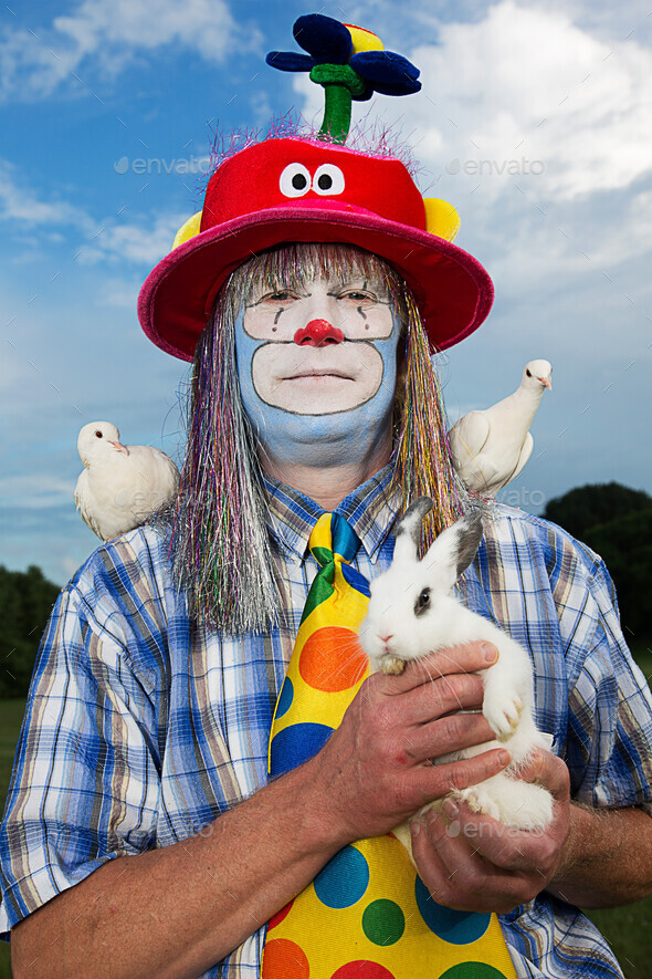Portrait of clown holding a rabbit and with doves on shoulders Stock ...