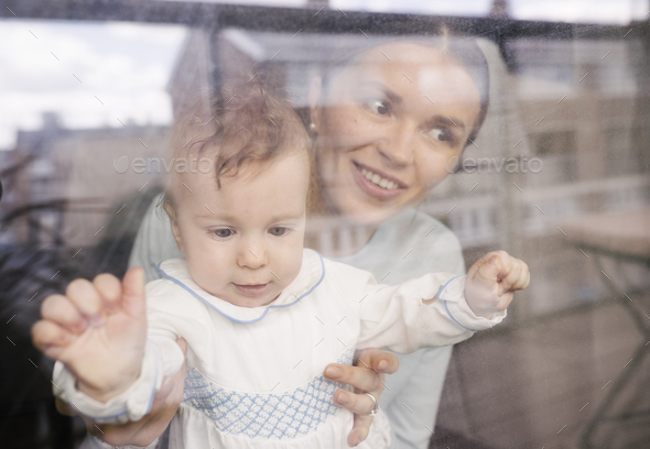 Mother and baby looking through glass window Stock Photo by Image-Source