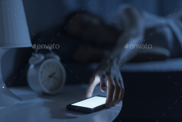 Woman receiving a phone call late at night Stock Photo by stokkete