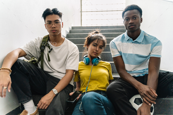 three multi ethnic Asian and African teenager students sitting on the ...