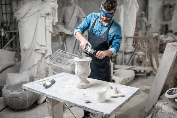 Sculptor working with sculptures in the studio Stock Photo by RossHelen