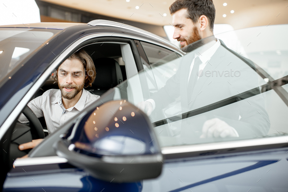 Man client with salesperson choosing car in the showroom Stock Photo by ...