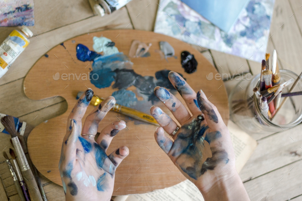 Closeup of female hands mixing paint on a palette at workshop. Artist ...