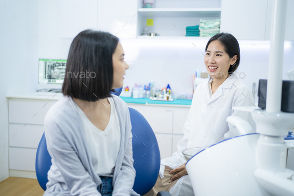 Caucasian beautiful girl talks and consult with Asian female dentist ...