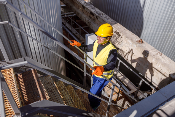 Joyful male worker climbing stairs at factory Stock Photo by ...
