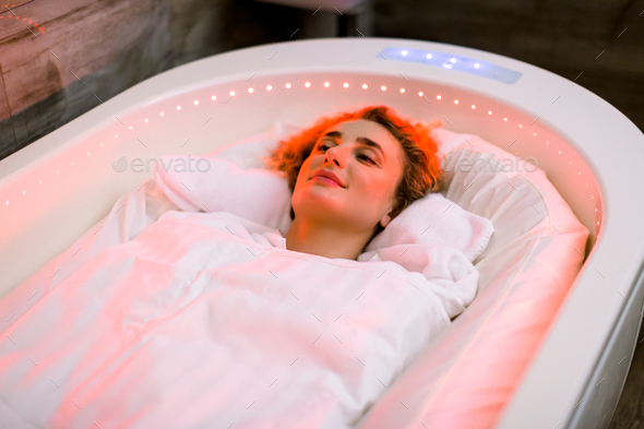 Beautiful woman, covered with special hot blanket lying on the spa bed ...