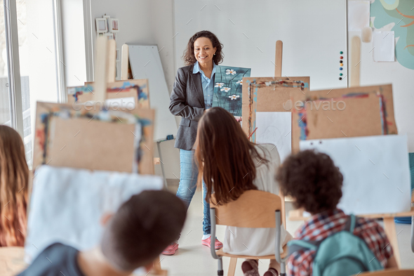 Young creative happy pupils at light modern classroom are doing drawing ...