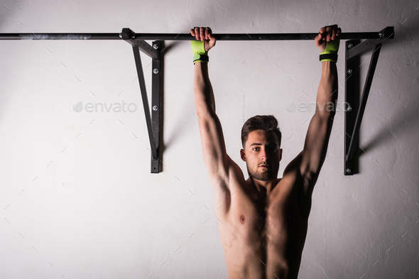Man hanging on bar near wall in gym Stock Photo by ADDICTIVE_STOCK