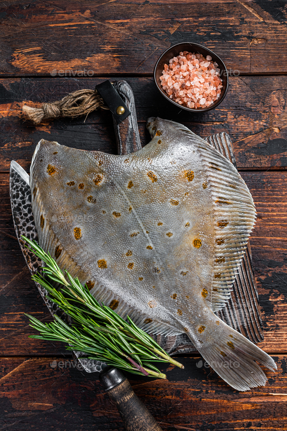 Raw plaice flatfish fish on butcher board with knife. Dark wooden ...
