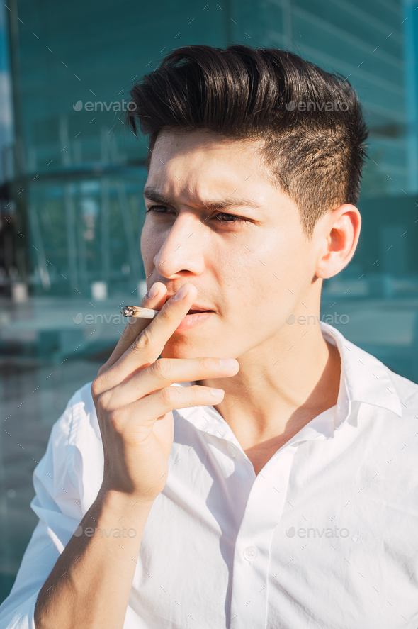 Handsome young man smoking cigarette Stock Photo by ADDICTIVE_STOCK