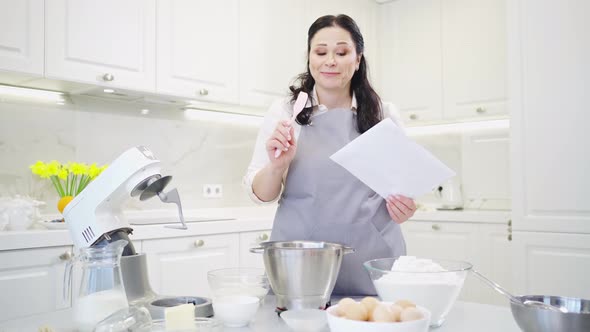 a Woman Cook with a Recipe Ingredients and a Mixer Prepares Pastries ...
