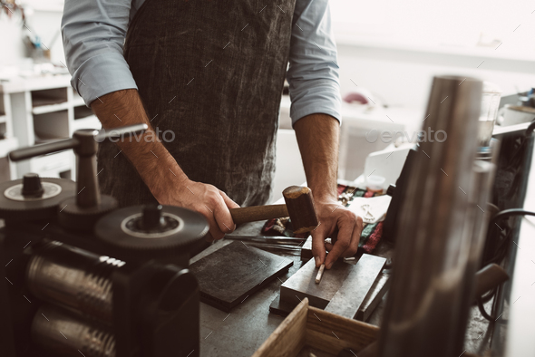 Important stage in the work. Male goldsmith wearing apron making a new ...