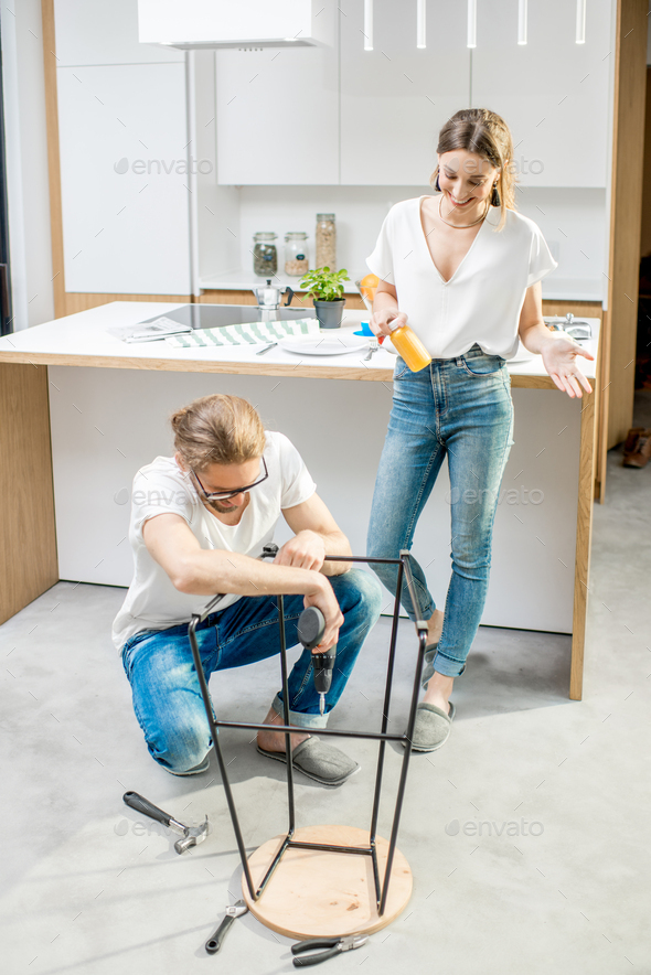 Couple doing house chores at the modern apartment Stock Photo by RossHelen