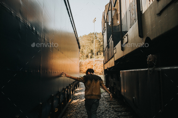 Back view of a man walking between trains Stock Photo by scopioimages