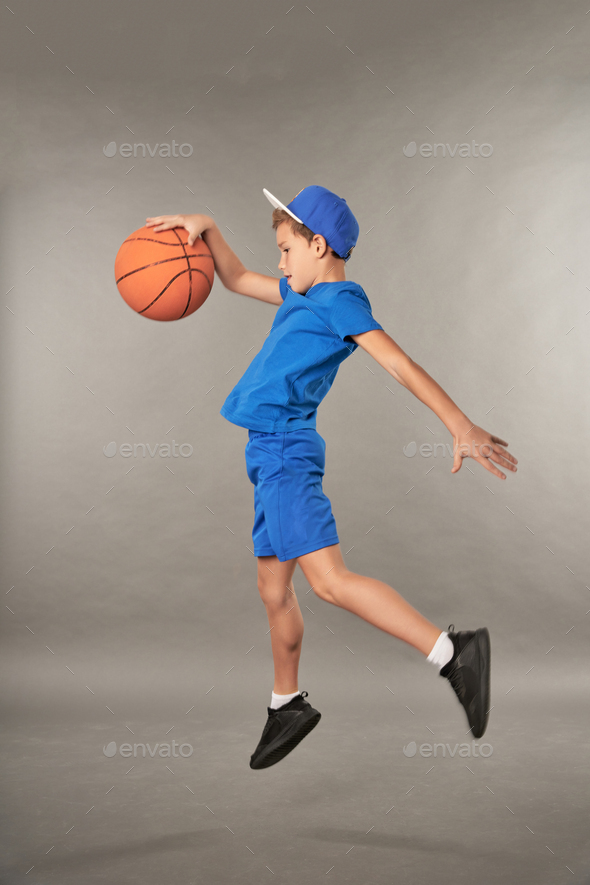 Adorable boy playing basketball against gray background Stock Photo by ...