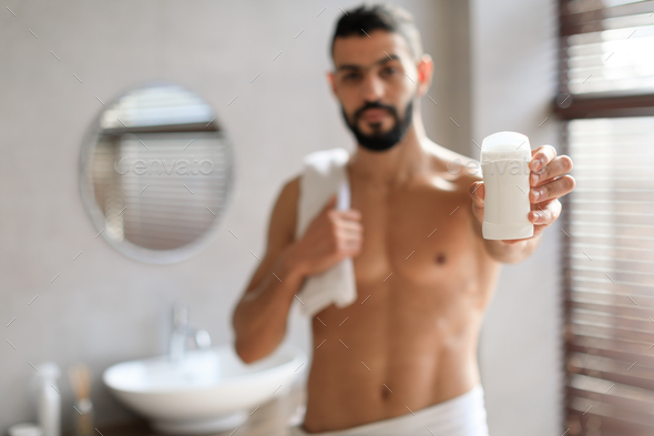 Handsome young guy standing with deodorant bottle in hand Stock Photo ...