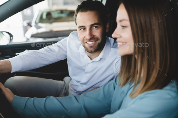 Loving husband teaching his wife girlfriend driving a car at the wheel ...