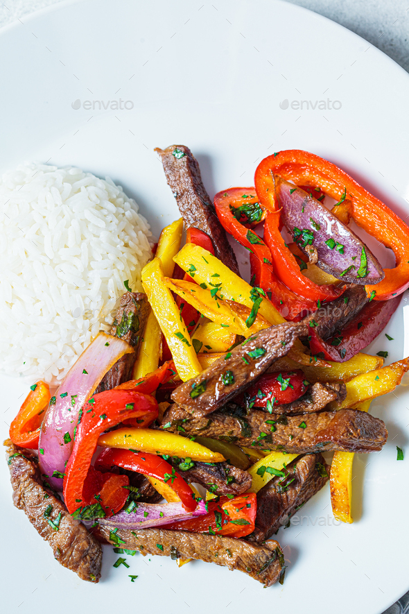 Lomo saltado - fried pieces of beef with peppers, onions and potatoes ...