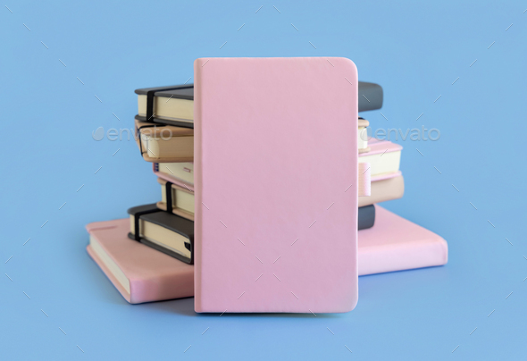Stack of pink and grey notebooks on light blue closeup. Textbook mockup ...
