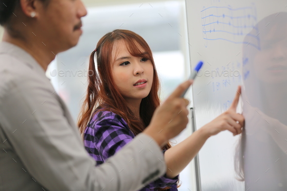 Teacher writing on board during lesson Stock Photo by FoToArtist_1