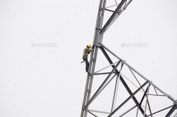 Pylon construction workers working on the top of power tower. Stock ...