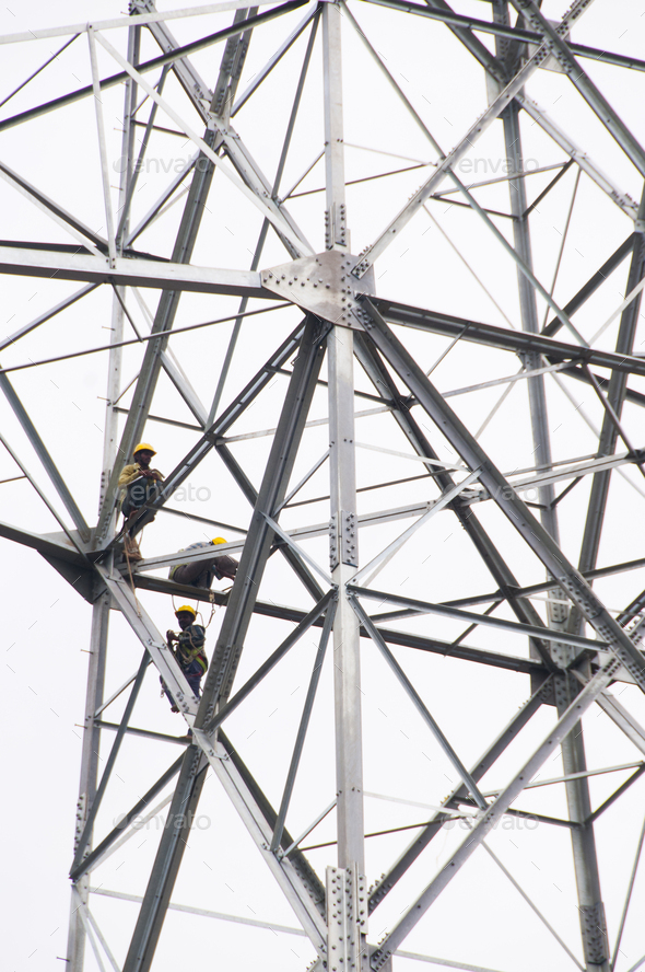 Pylon construction workers working on the top of power tower. Stock ...