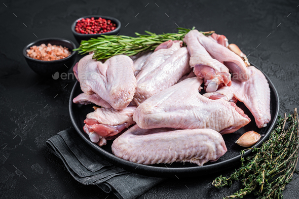 Raw duck wings on a plate with herbs. Black background. Top view Stock ...