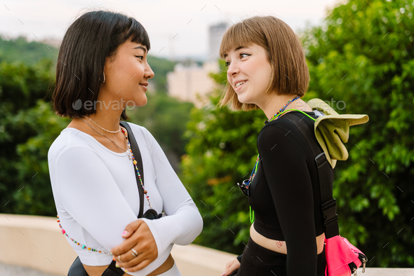 Multiracial two women talking and smiling while walking together Stock ...
