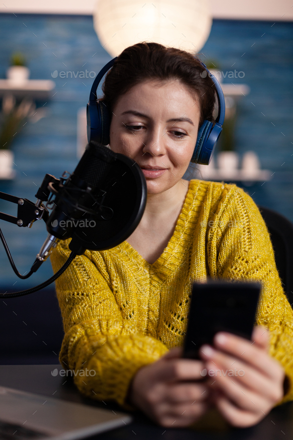 Portrait of social media influencer with headphones holding smartphone ...