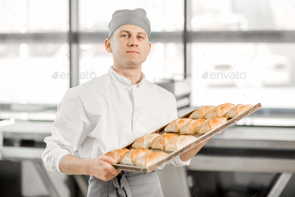 Baker with buns at the manufacturing Stock Photo by RossHelen | PhotoDune