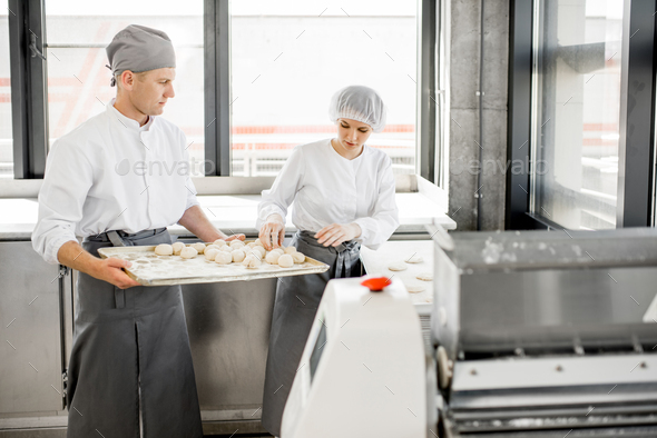 Bakers rolling dough at the manufacturing Stock Photo by RossHelen