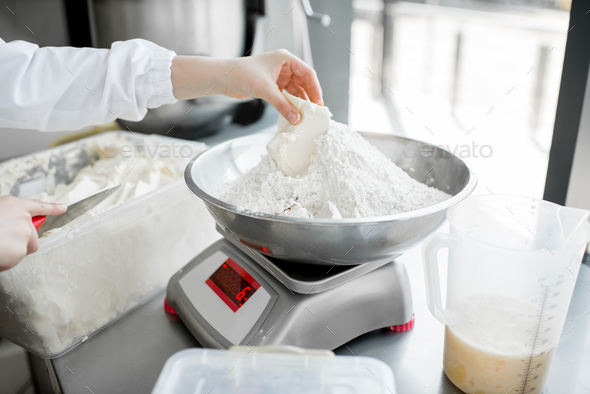 Weighing flour for baking at the manufacturing Stock Photo by RossHelen