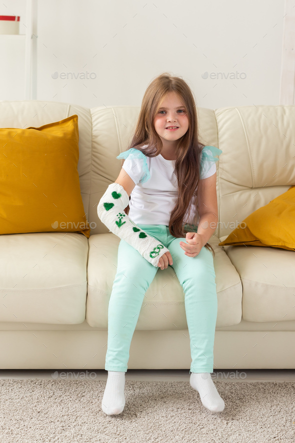 Child with a cast on a broken wrist or arm smiling and having fun on a ...