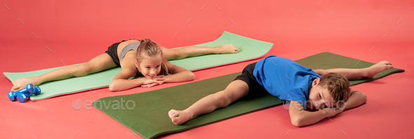 Adorable boy and girl doing the splits against red background Stock ...