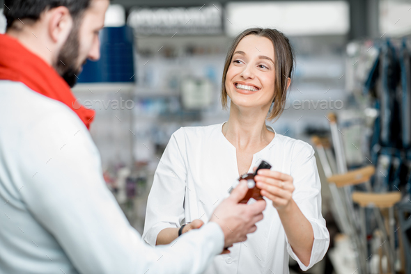 Pharmacist with client in the pharmacy store Stock Photo by RossHelen