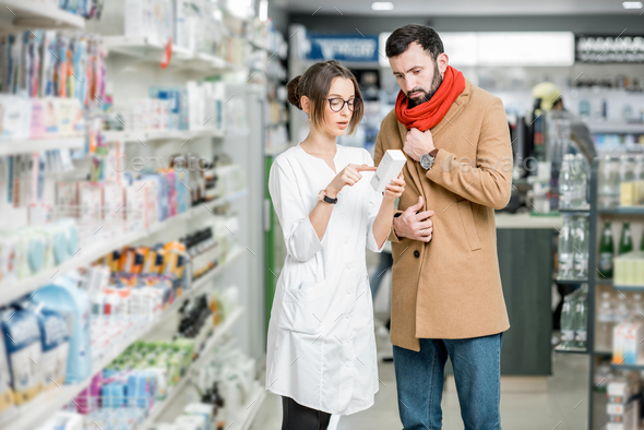 Pharmacist with client in the pharmacy store Stock Photo by RossHelen