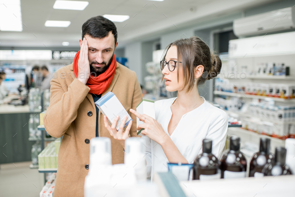 Pharmacist with client in the pharmacy store Stock Photo by RossHelen