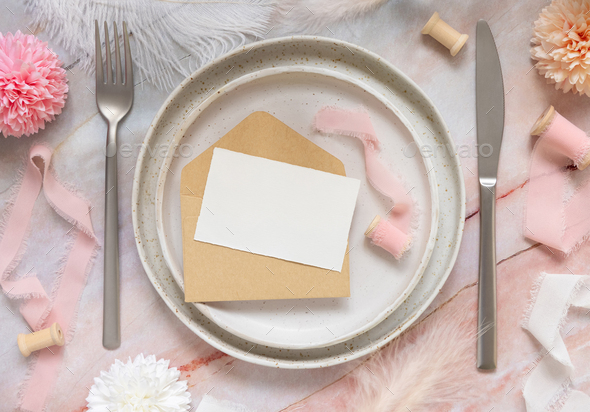 Wedding Table place with a card over envelope near flowers and feathers ...