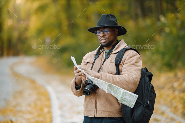 Black man standing on a road and holding a map Stock Photo by prostooleh