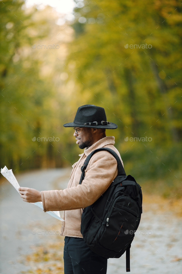 Black man standing on a road and holding a map Stock Photo by prostooleh