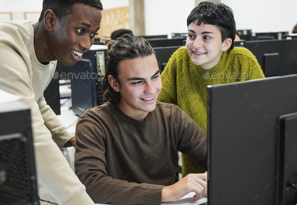 Young diverse students learning together inside computer class room ...
