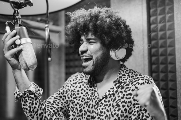 Male singer using microphone and headphone recording audio inside music ...