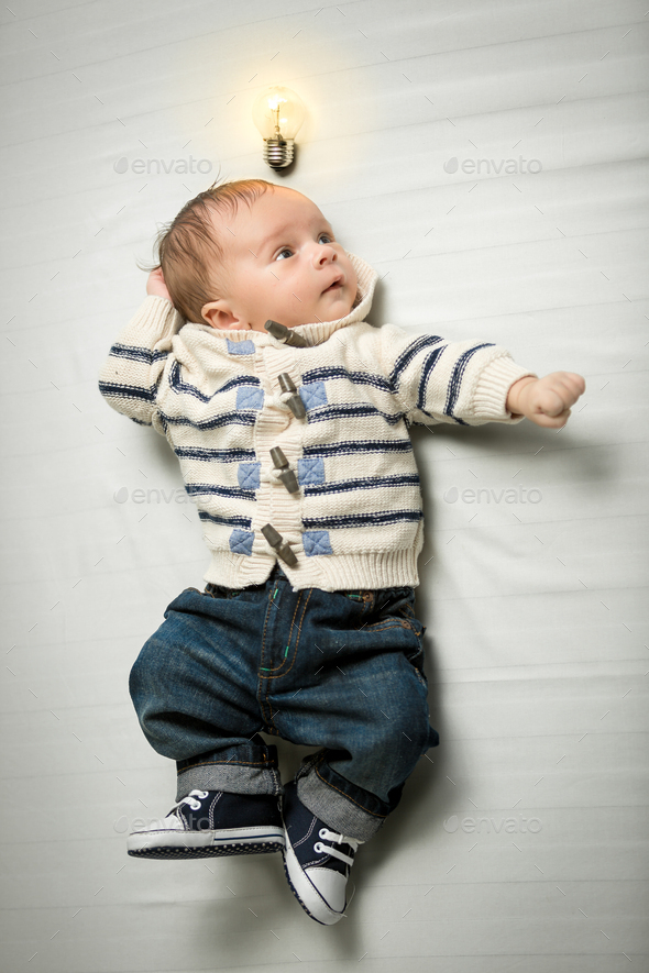 cute baby boy posing on bed with glowing light bulb overhead Stock ...