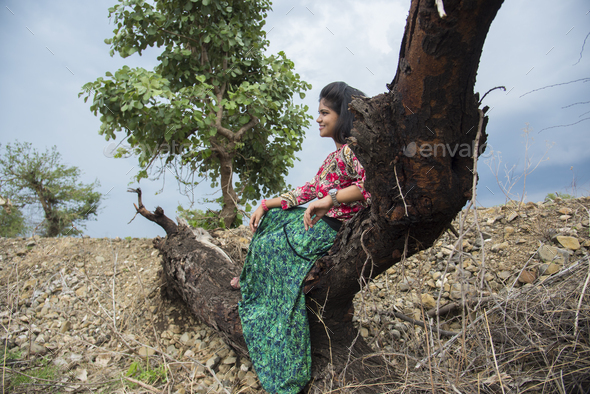 Beautiful young girl wear traditional dress and lying on tree trunk ...