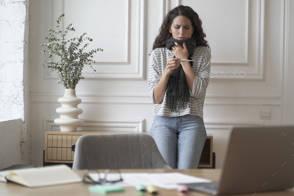 Sick woman freelance worker with fever measuring high temperature while ...
