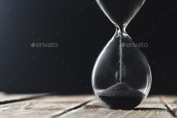 Modern hourglass on wooden background Stock Photo by FabrikaPhoto ...
