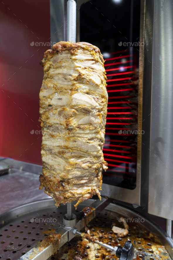Rotating skewered chicken meat grilled in stainless steel grill and ...